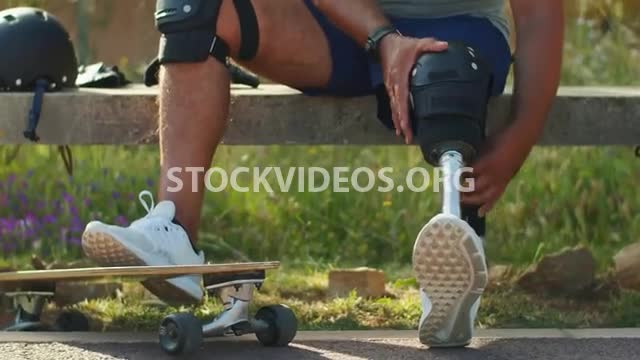 Man with prosthetic leg putting knee protection pads on, amputee ...