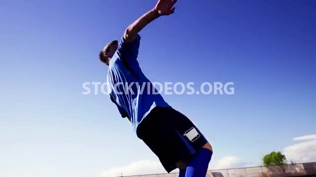 Slow motion of soccer player kicking ball mid air, footballer jumping ...